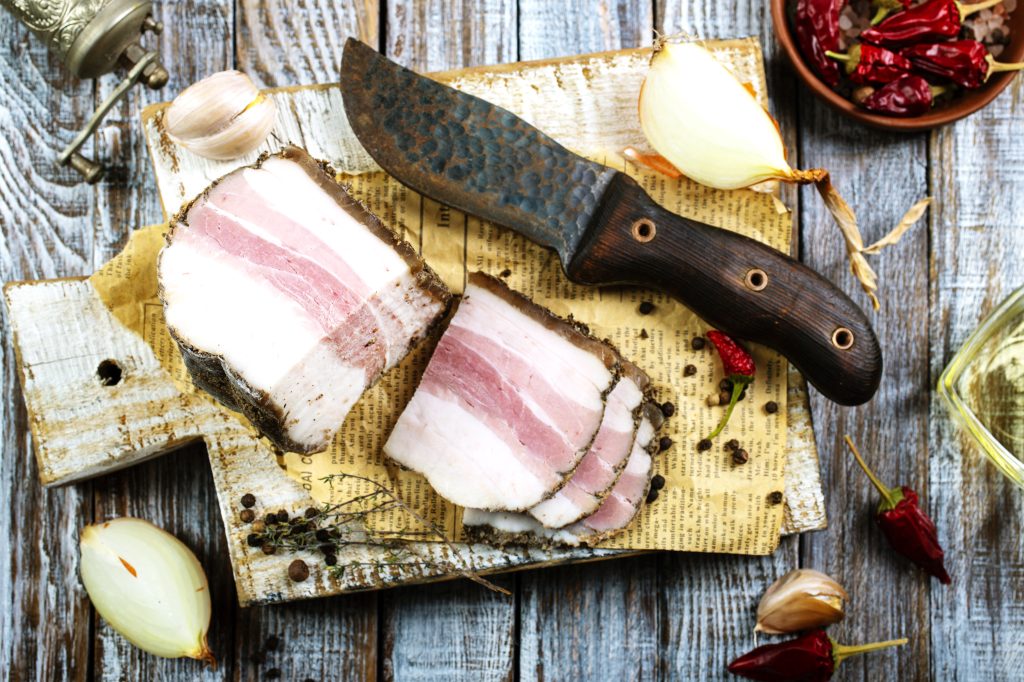 Chunks of salted bacon on dark background. Healthy food with pranami ...